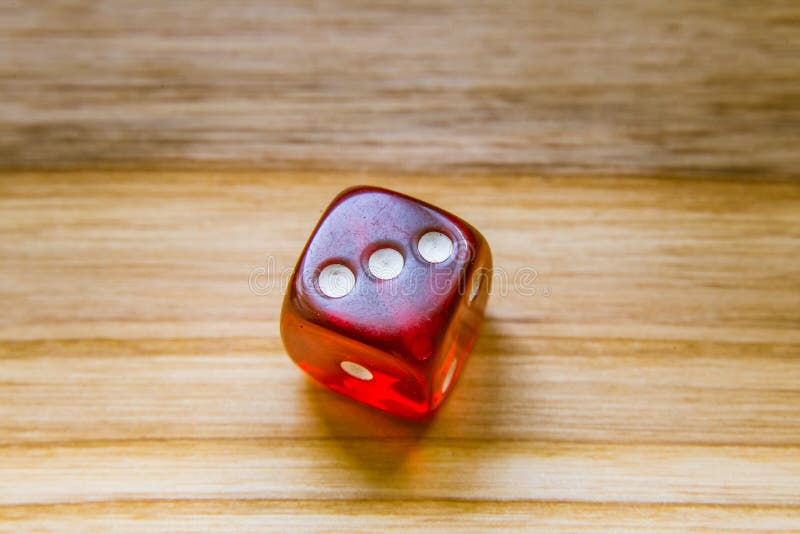 A Translucent Red Six Sided Playing Dice on a Wooden Background Stock ...
