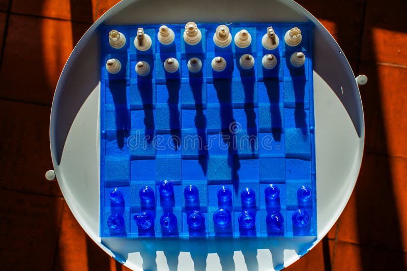 A Transparent Blue Chessboard with Contrasting White and Blue Pieces ...