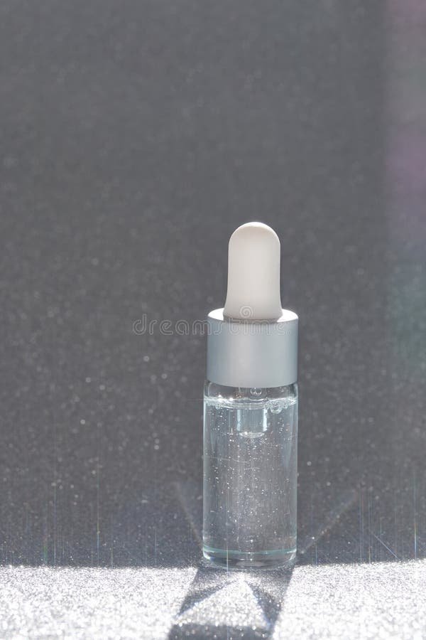 Transparent Serum Bottle with Dropper on Glittering Surface in Sunlight ...