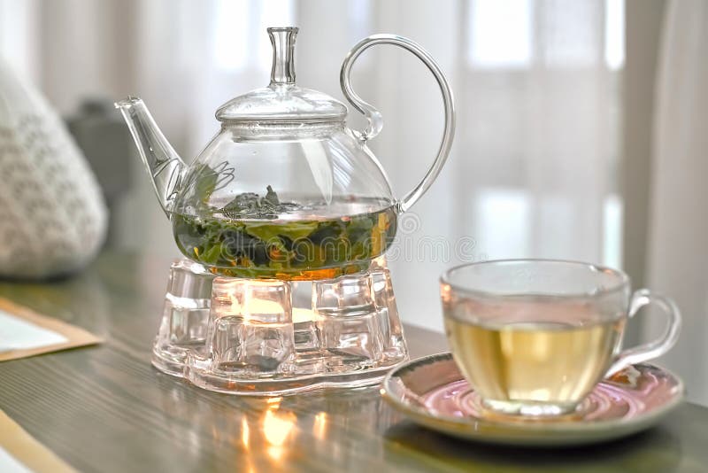 Transparent Teapot with Green Tea on a Stand with a Candle, Close-up ...