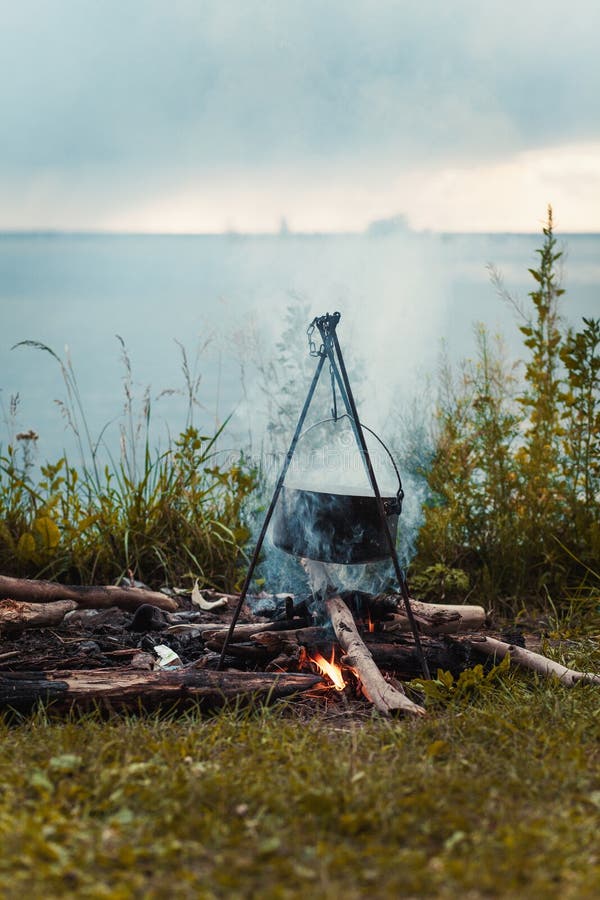 Travel a Kettle Over a Fire Burning on the River and Sunset Backgroun ...