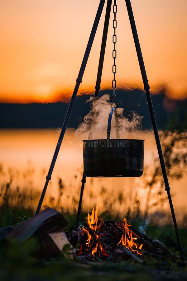 Travel a Kettle Over a Fire Burning on the River and Sunset Backgroun ...