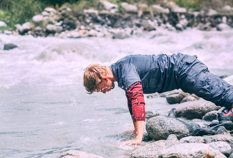 Traveler Man Washes His Face with Cold Water in Mountain River Stock ...