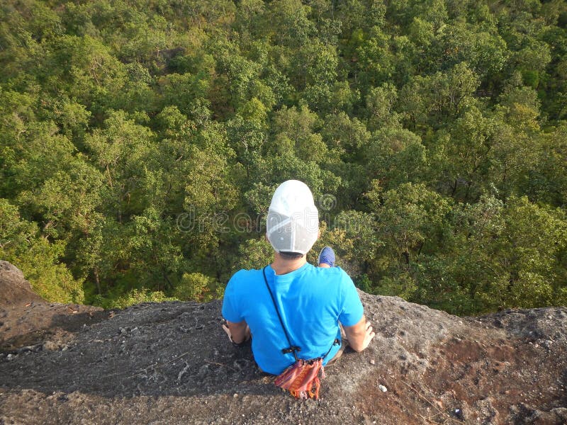 Traveller Sitting at the Edge of a Cliff Looking Down on Green Trees ...