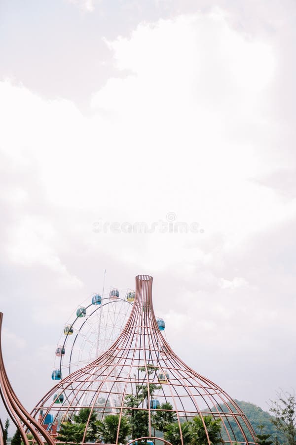A Tree Cage and Ferris Wheel with a Backdrop of Slightly Cloudy Skies ...
