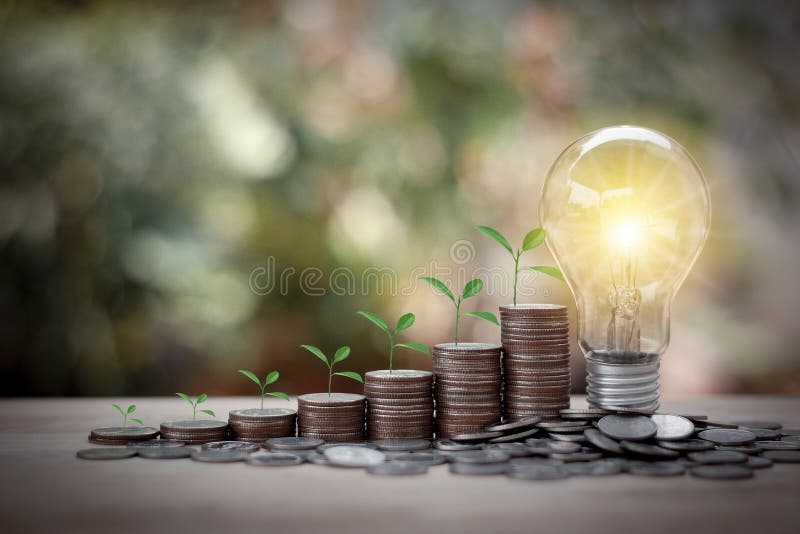 Tree Growing On Stacks Of Coins And Energy Saving Light Bulb With Bokeh ... Tree Growing On Stacks Of Coins And Energy Saving Light Bulb With Bokeh ...