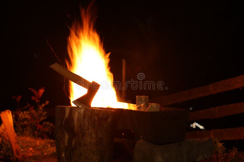 Tree Stump with Axe and Burning Firewood in Metal Brazier Outdoors at ...