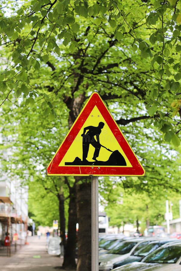 Triangle Road Construction Sign on a Post at a Street with Trees Stock ...