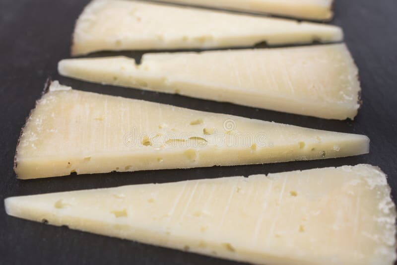 Triangle-shaped Slices of Aged Spanish Manchego Cheese on a Dark Stone ...
