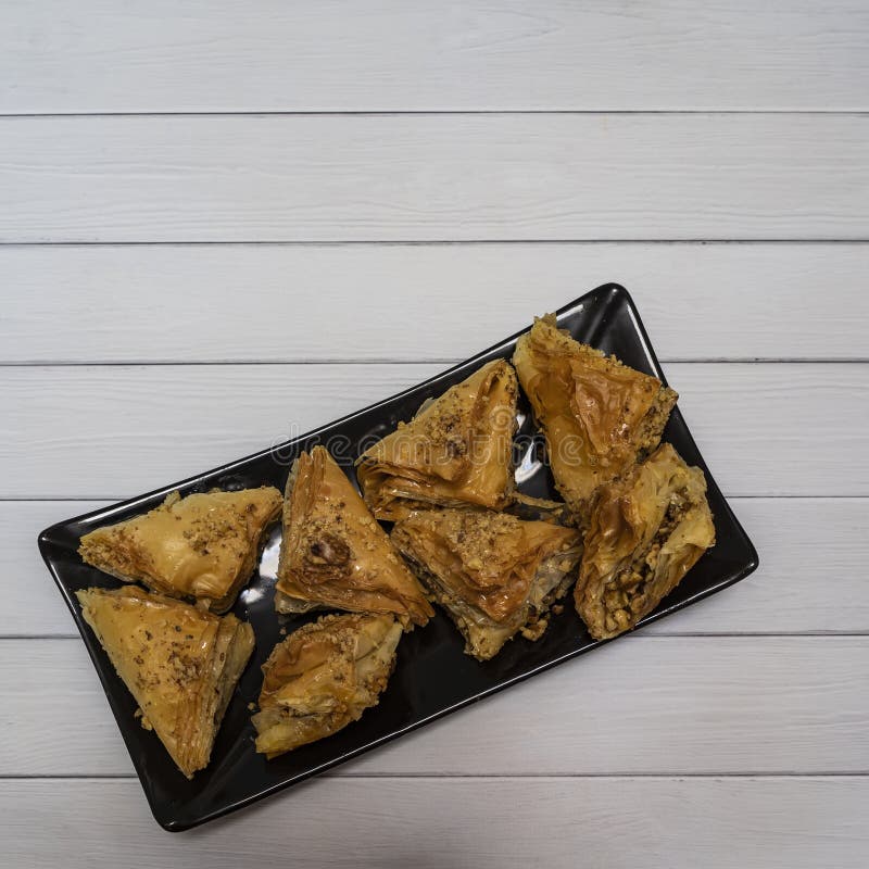 Triangular Puff Pastry Cookies with Nuts are Stacked on a Black ...