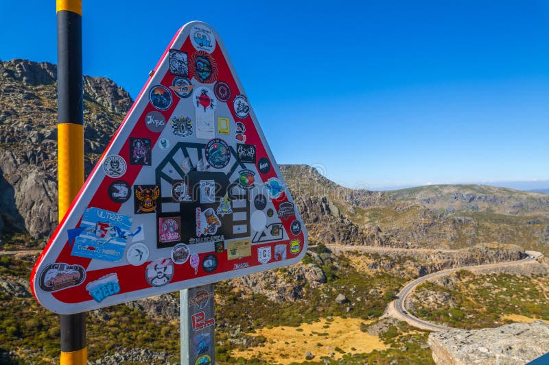A Triangular Road Sign Covered in Various Stickers Stands Against a ...