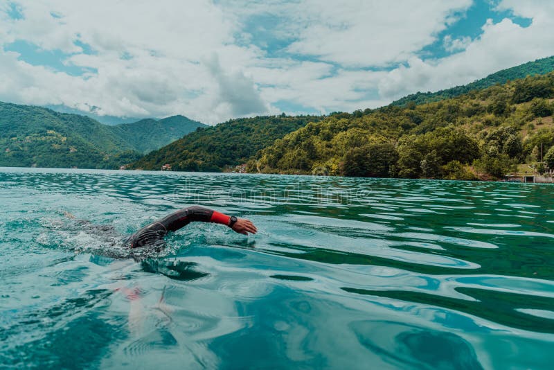 A Triathlete in a Professional Swimming Suit Trains on the River while ...