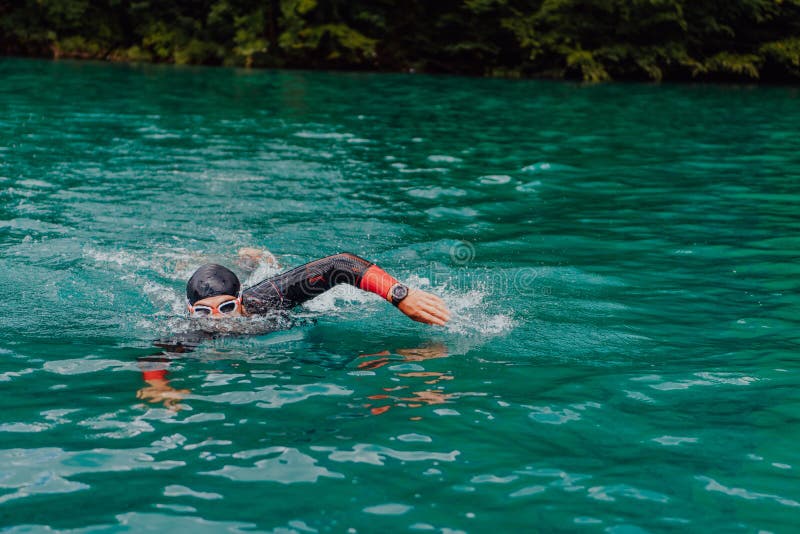 A Triathlete in a Professional Swimming Suit Trains on the River while ...