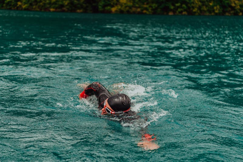A Triathlete in a Professional Swimming Suit Trains on the River while ...