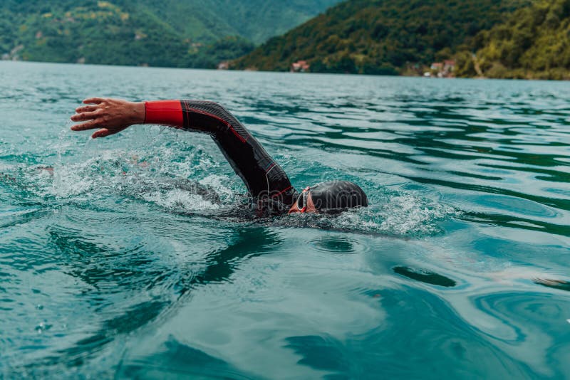 A Triathlete in a Professional Swimming Suit Trains on the River while ...