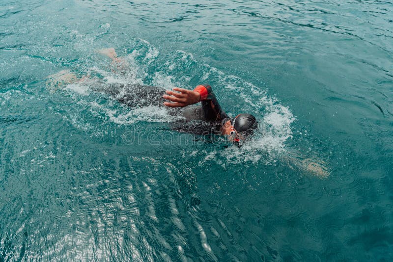 A Triathlete in a Professional Swimming Suit Trains on the River while ...