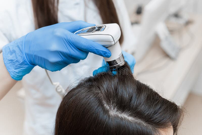 A Trichologist with a Trichoscope Examines a Girl`s Long Hair Stock ...