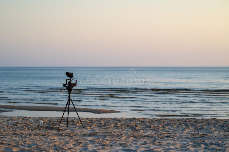 Tripod with Camera Stands on the Beach at Sunrise and Shoots the Sea ...