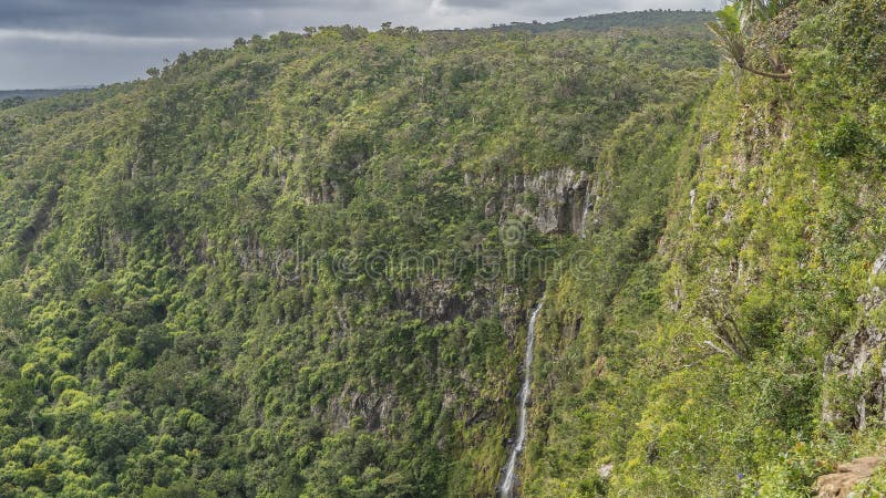A Tropical Waterfall. a Thin Stream Flows Down a Steep Mountainside ...