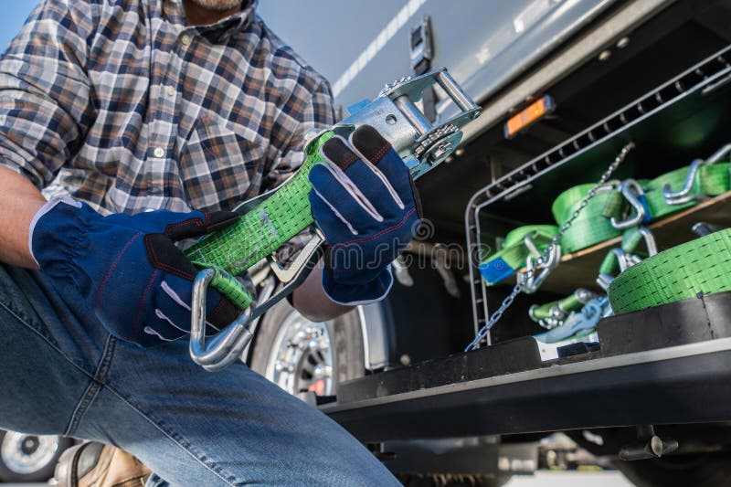 A Truck Driver Securing Cargo with Ratchet Straps in an Outdoor Setting ...