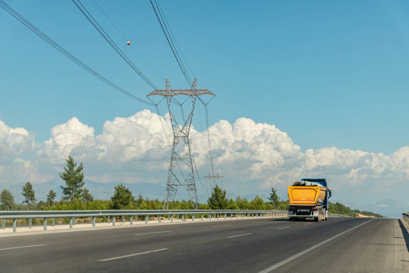 A Truck Going on a Highway and a High-voltage Power Line on the Side of ...