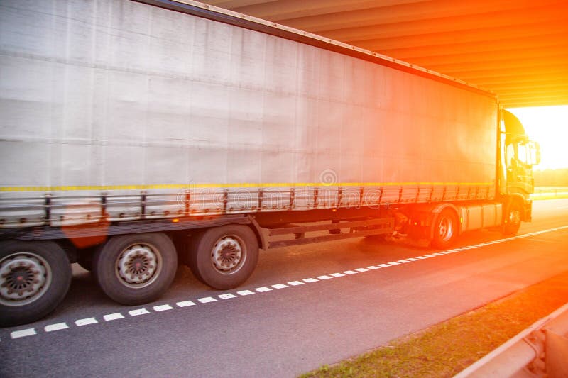 A Truck with a Semi-trailer Drives Under a Bridge Against the Backdrop ...