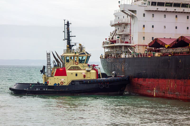 Tug Boat Assisting Huge Ship in Port Stock Photo - Image of work ...