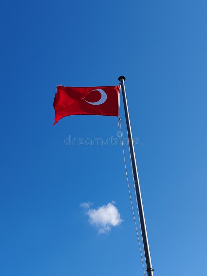 The Turkish Flag Flies in the Wind on Flagpole Against the Blue Sky and ...