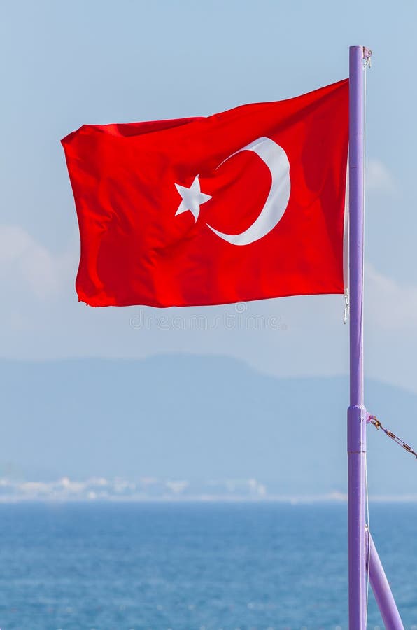 The Turkish Flag Flies in the Wind on Flagpole Against the Blue Sky and ...
