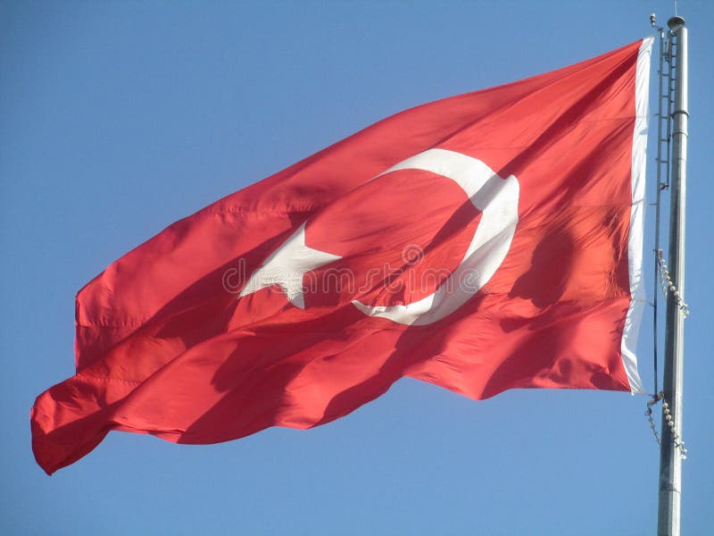 The Turkish Flag Flies in the Wind on Flagpole Against the Blue Sky and ...
