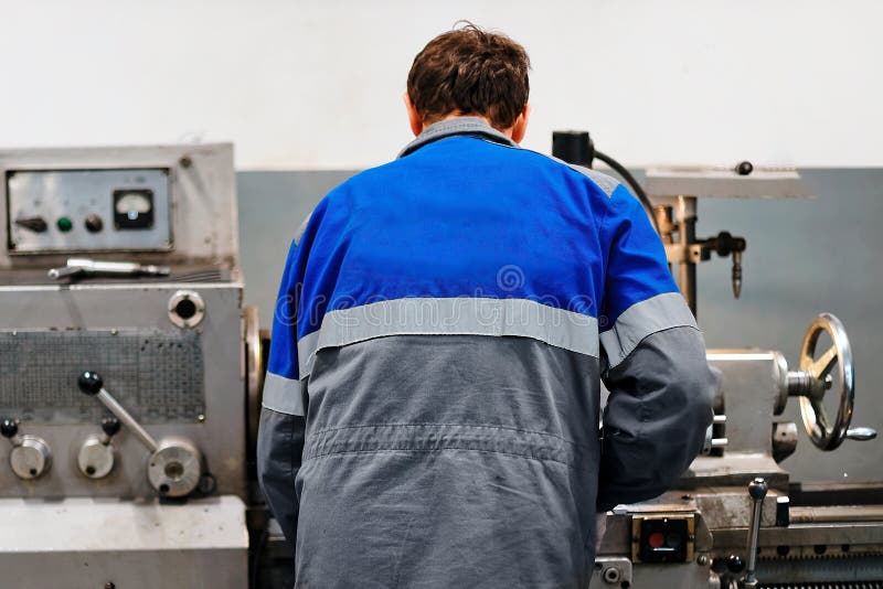 Turner Stands Behind Lathe in Production Hall and Works. View of Worker ...