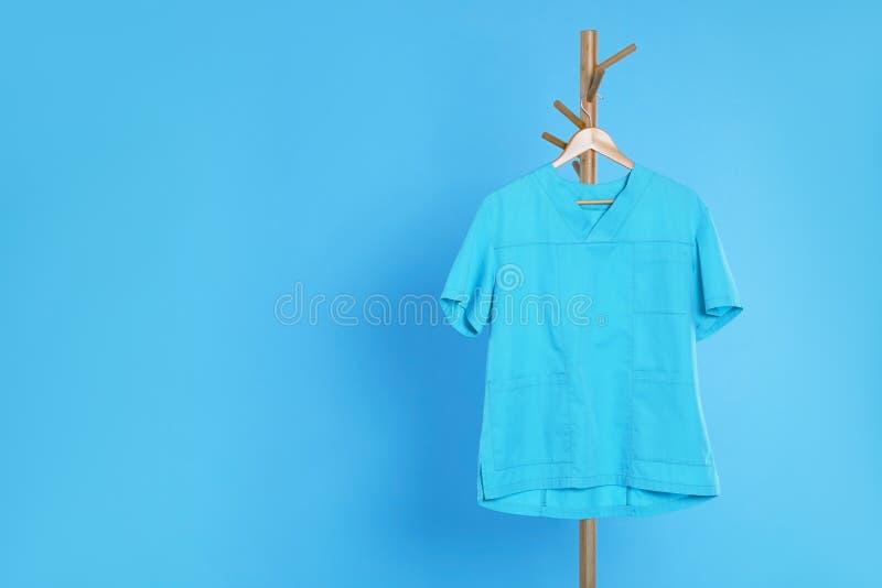 Turquoise Medical Uniform Hanging on Rack Against Light Blue Background ...