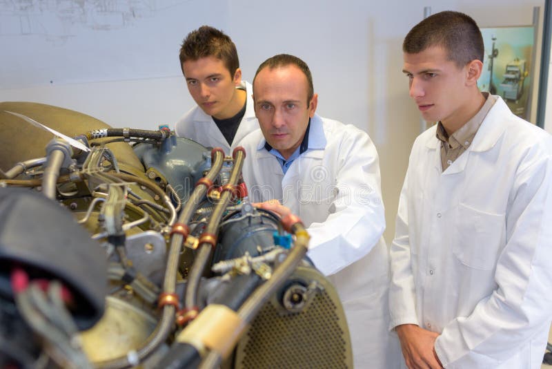 Tutor with Apprentices Looking at Mechanical Object Stock Photo - Image ...