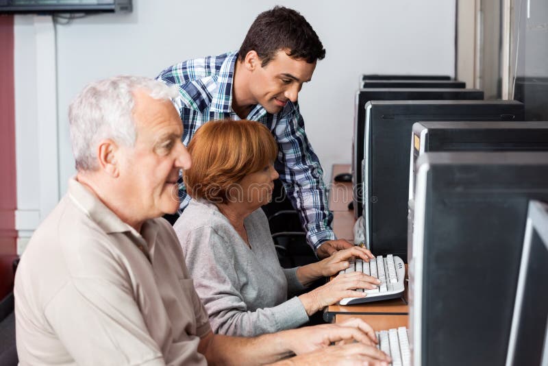 Tutor Assisting Senior Woman in Using Computer Stock Photo - Image of ...
