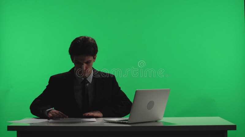 TV Presenter Sits at a Table in a Dark Studio Against a Green Screen. a ...