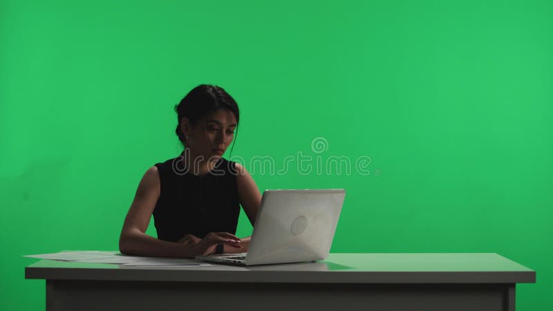 TV Presenter Sits at a Table in a Dark Studio Against a Green Screen. a ...