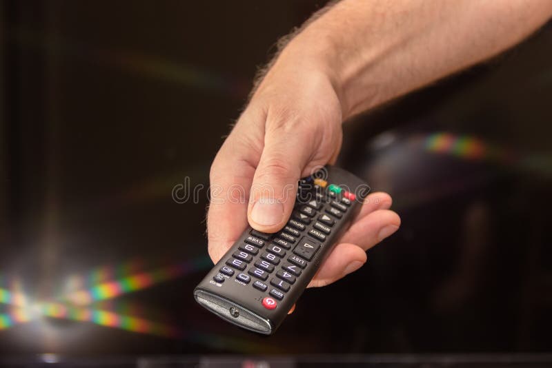 TV Remote Controller in Hand on a Blurred Dark Background Stock Photo ...