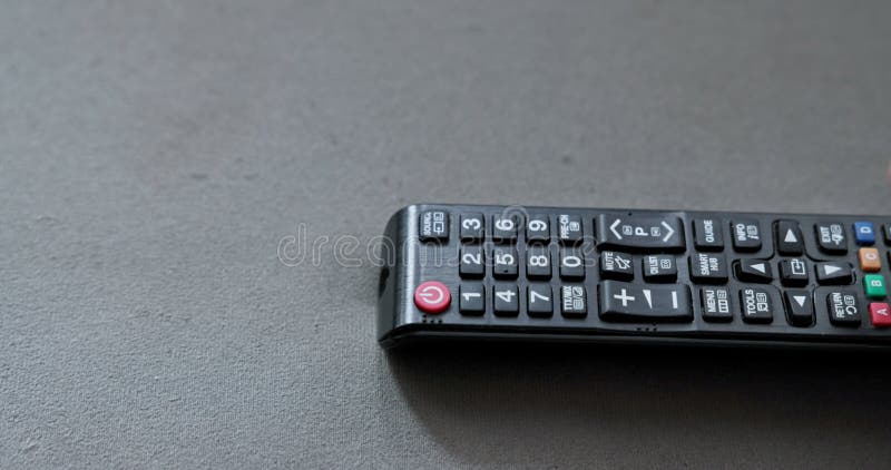 The TV Remote is Lying on the Sofa and the Man is Pressing the Power ...