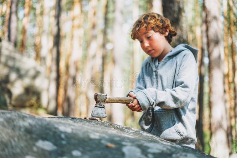 Tween Boy in Casual Outfit Cuts Stick with Axe on Rock in the Forest ...