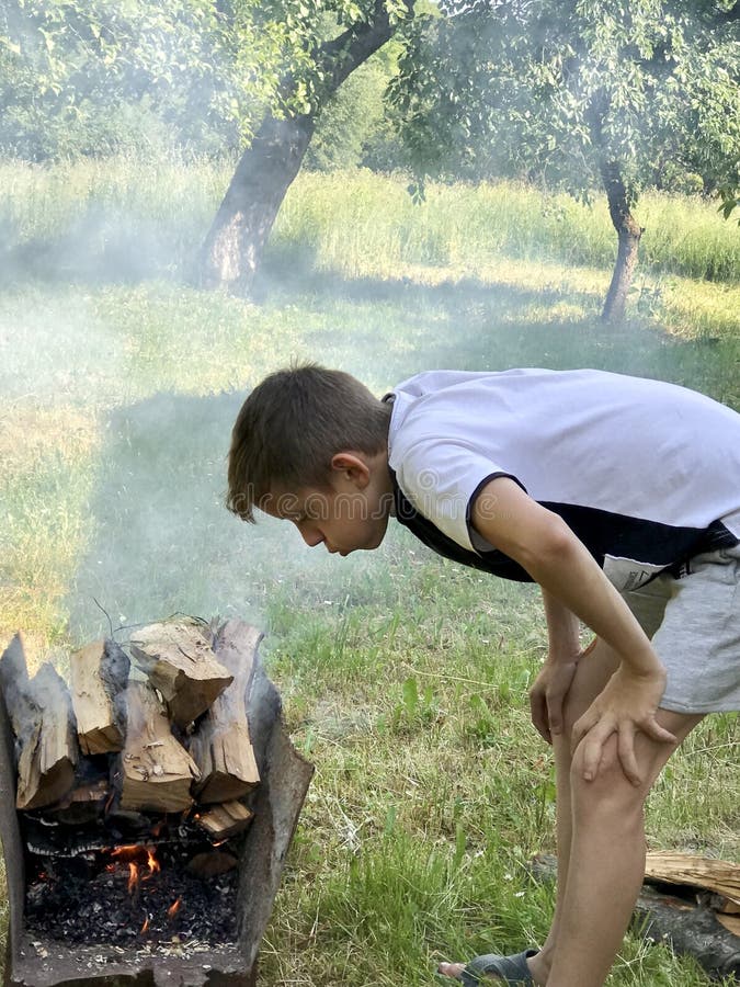 A Twelve-year-old Boy Blows while Lighting a Fire in a Barbecue Grill ...