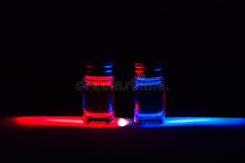 Two Abstract Red and Blue Glass Potions Under Colorful Light Stock ...