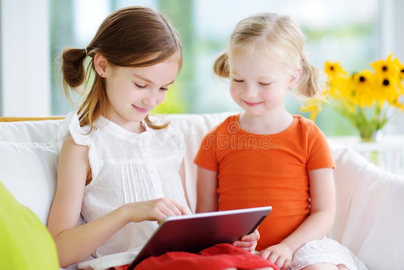 Two Adorable Little Sisters Playing with a Digital Tablet Stock Photo ...