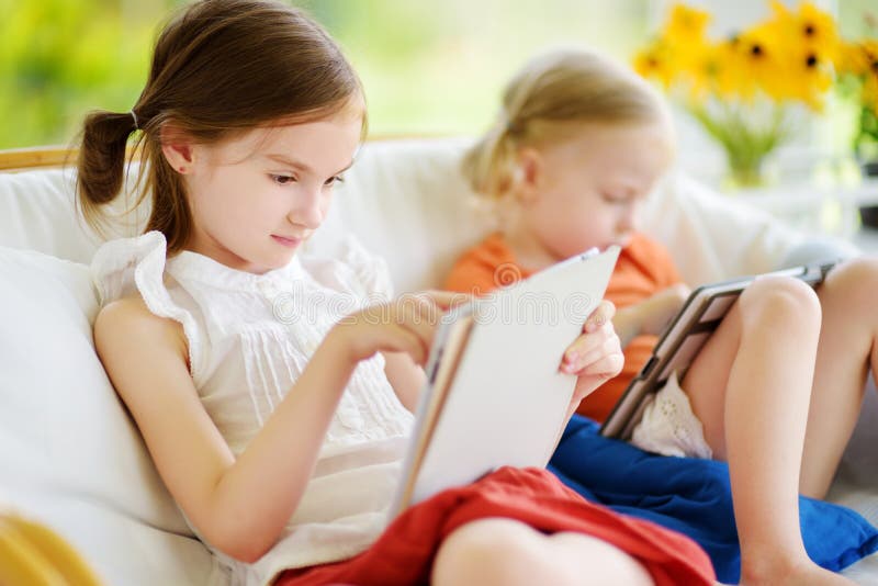 Two Adorable Little Sisters Playing with a Digital Tablet Stock Photo ...