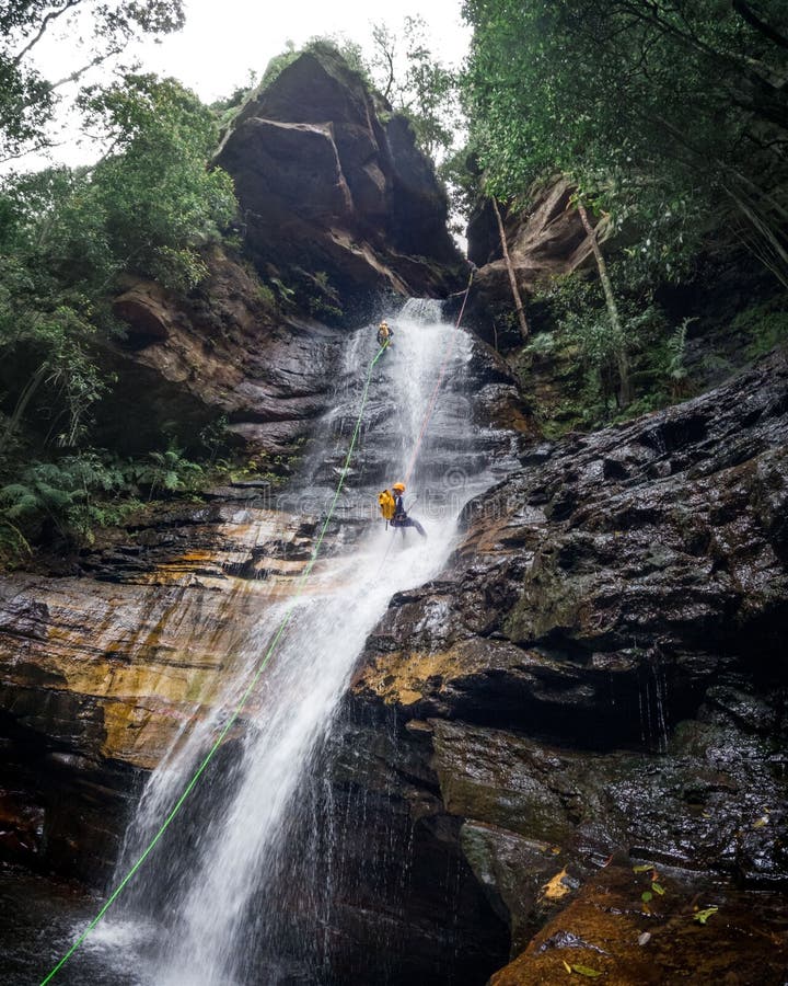 Two Adventurers Rappelling Down a Waterfall Stock Photo - Image of lush ...