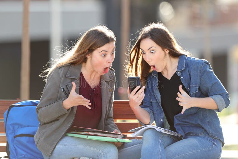 Two Amazed Students Checking Phone Content in a Park Stock Photo ...