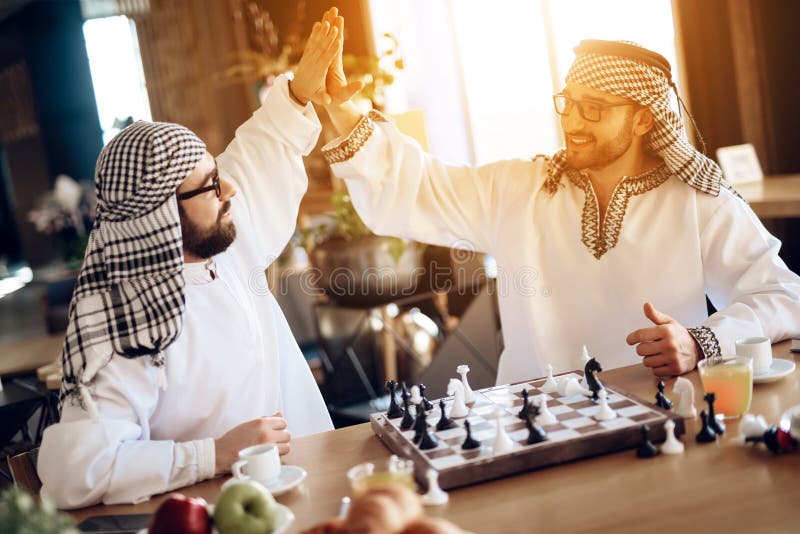 Two Arab Businessmen High Five Behind Chessboard at Hotel Room. Stock ...