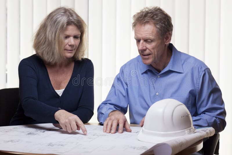 Two Engineers Discussing Plans with CMM Arm in Foreground Stock Photo ...