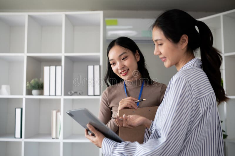 Two Asian Businesswomen Discussing Work Using a Tablet in a Modern ...