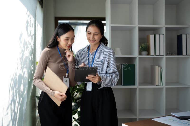 Two Asian Businesswomen Discussing Work Using a Tablet in a Modern ...