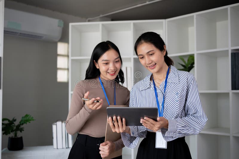Two Asian Businesswomen Discussing Work Using a Tablet in a Modern ...